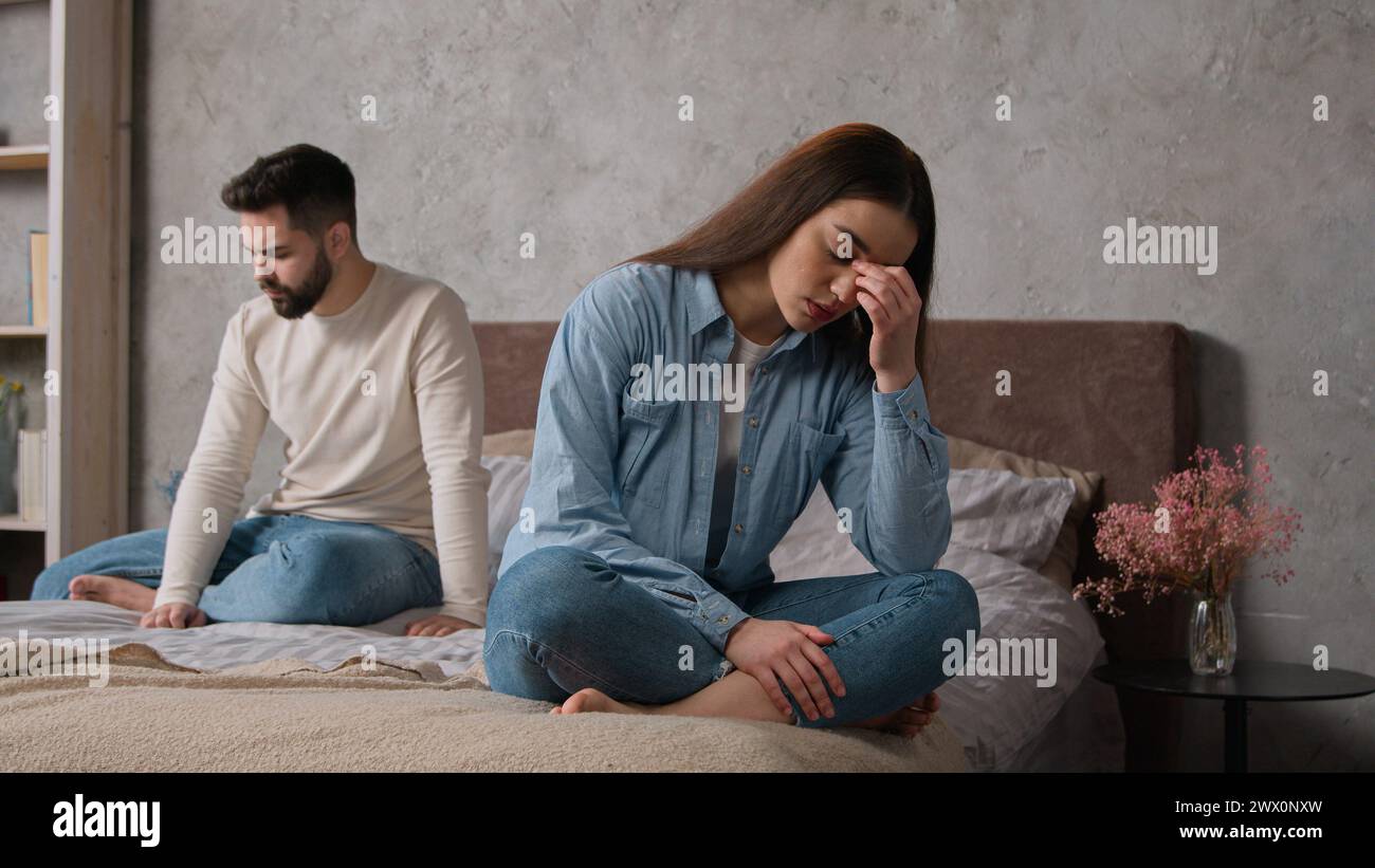 Sad annoyed Caucasian couple family spouses sit apart on bed offended ...