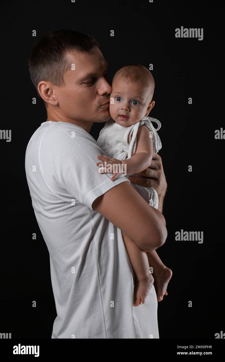 Happy father with his little baby on black background Stock Photo - Alamy