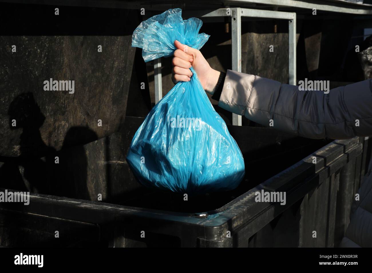 Woman throwing trash bag full of garbage in bin outdoors, closeup Stock ...
