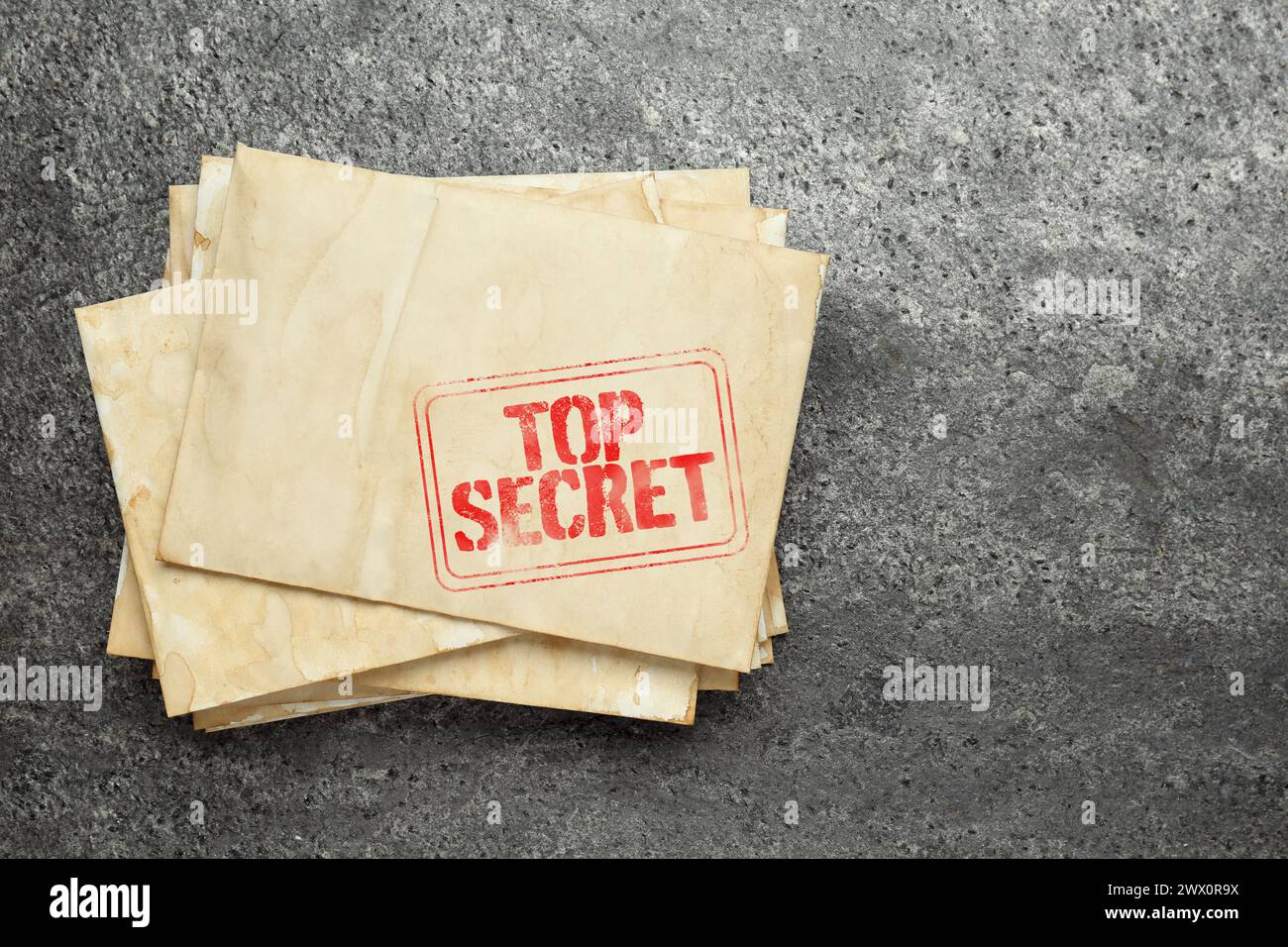 Top Secret stamp. Stacked old letters on grey table, top view. Space ...