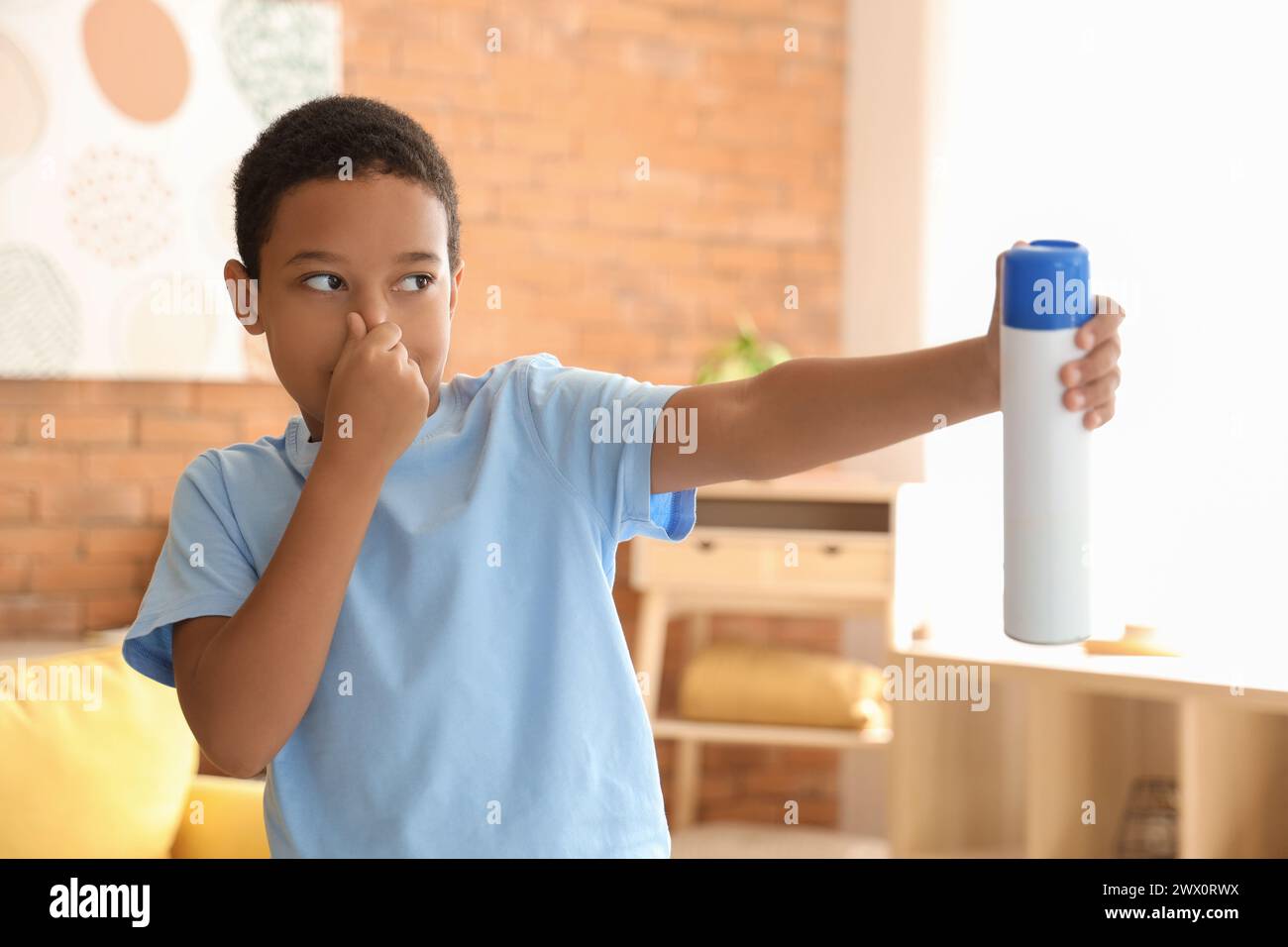 Little African-American boy disgusted by bad smell using air freshener ...