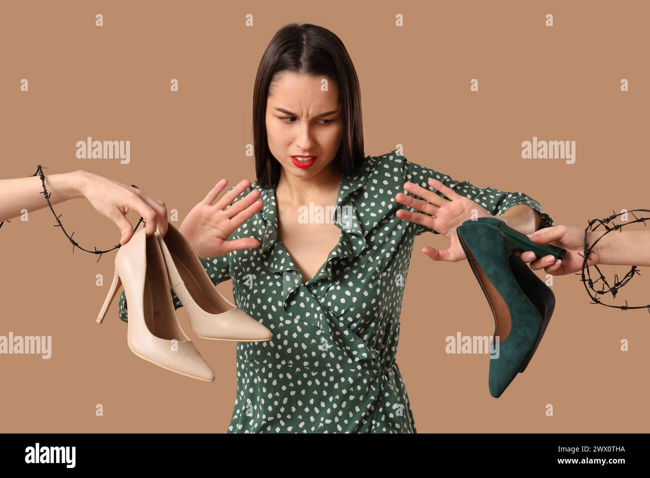 Displeased young woman rejecting shoes with barbed wire on beige ...
