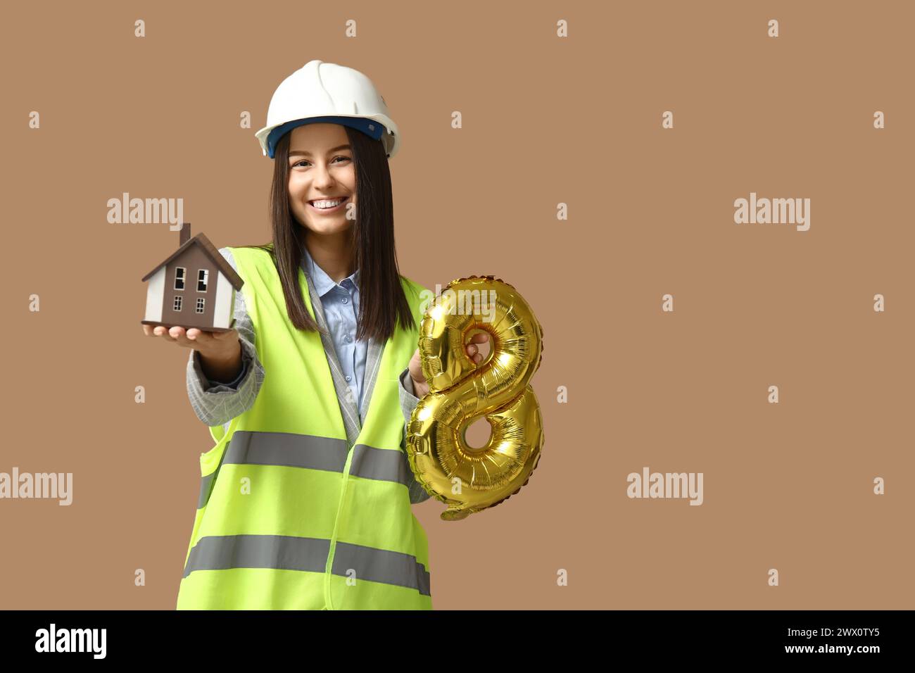 Female construction worker with toy house and balloon in shape of ...