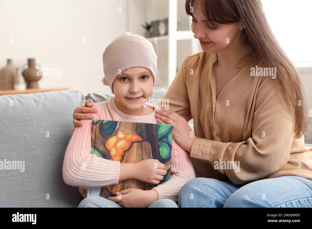 Little girl after chemotherapy with book and her mother at home ...