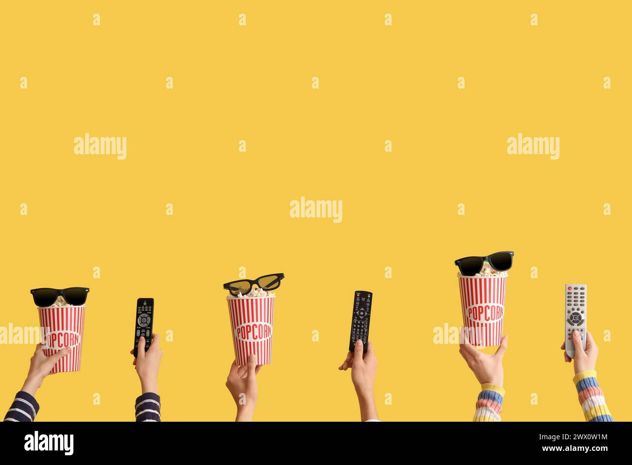Many hands with buckets of popcorn, TV remotes and 3D glasses on yellow ...
