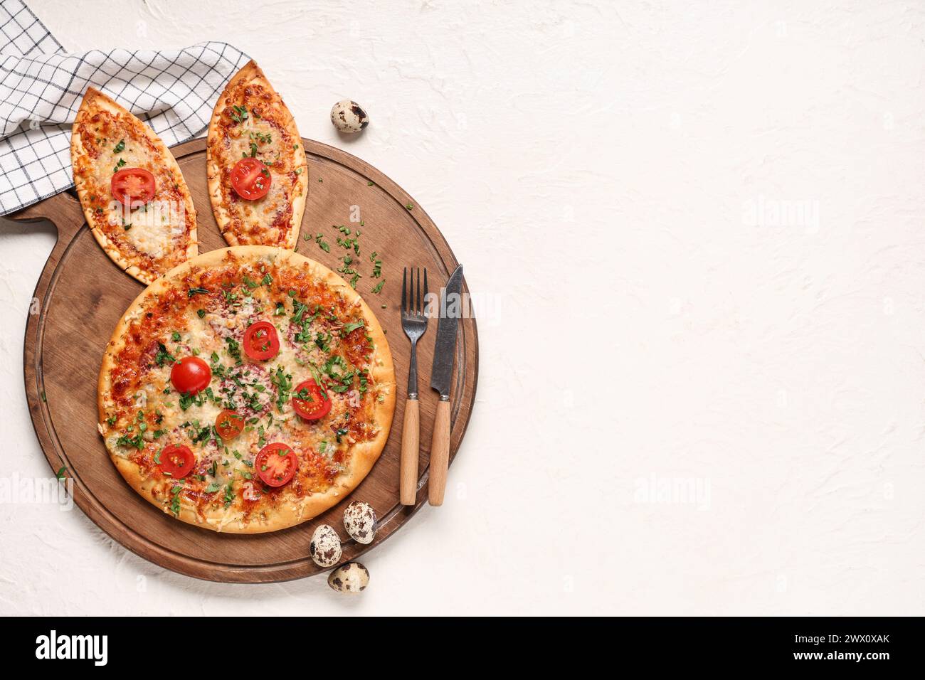 Board with tasty Easter pizza with bunny ears and cutlery on white ...
