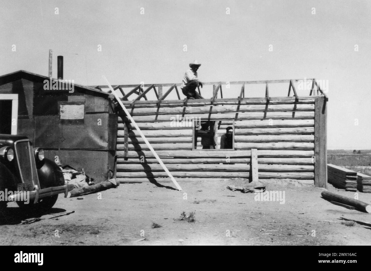 Men working on a roof during construction of a log cabin ca. 1940s ...