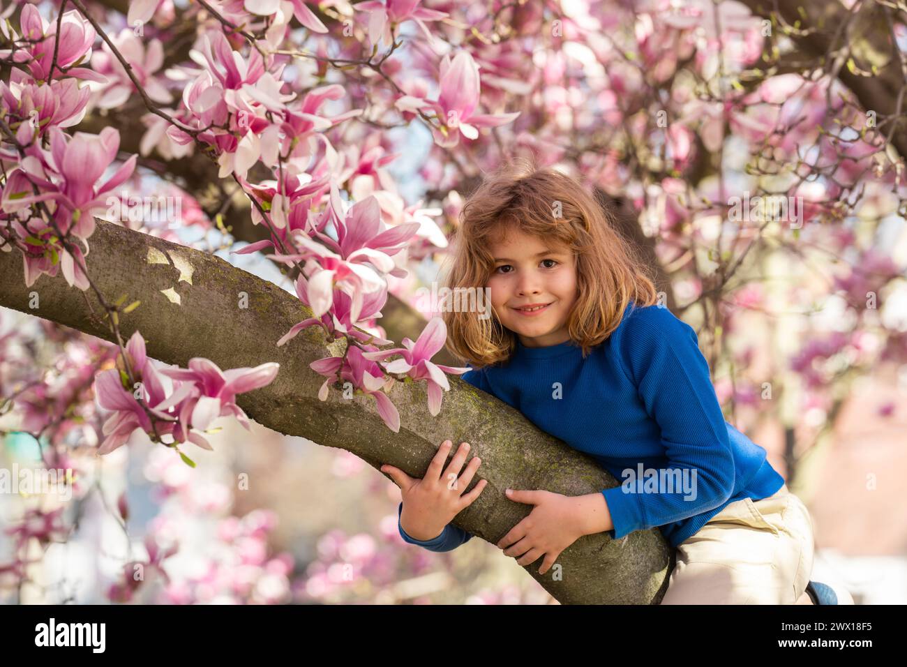 Little kid smelling spring flower outdoor. Portrait of smiling child ...
