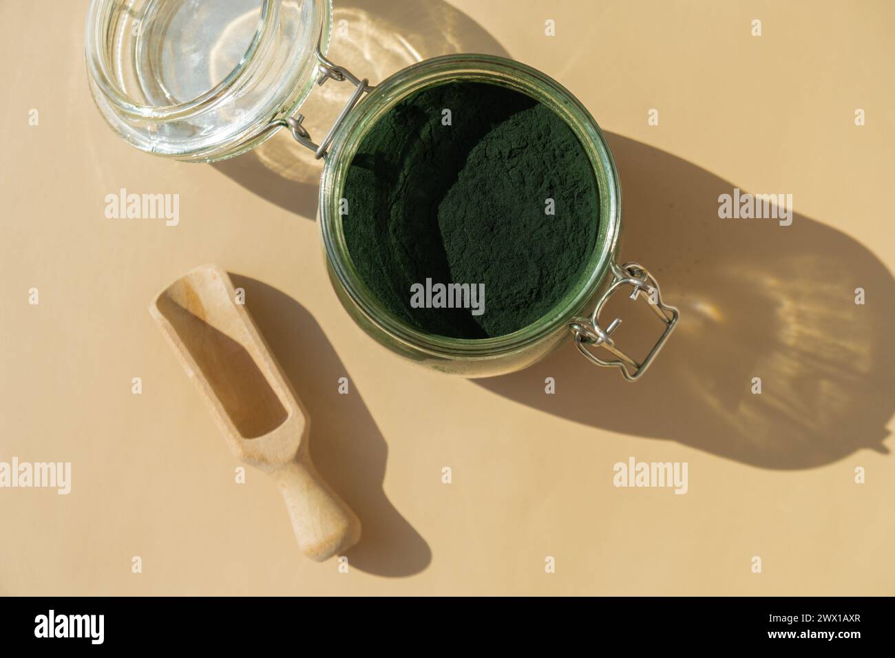 Organic blue-green algae spirulina powder food in glass jar with wooden ...