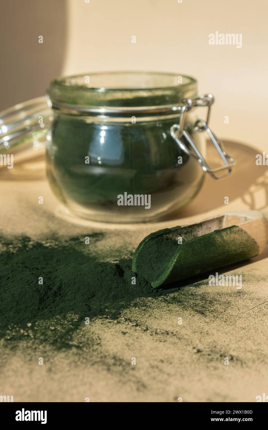 Organic blue-green algae spirulina powder food in glass jar with wooden ...