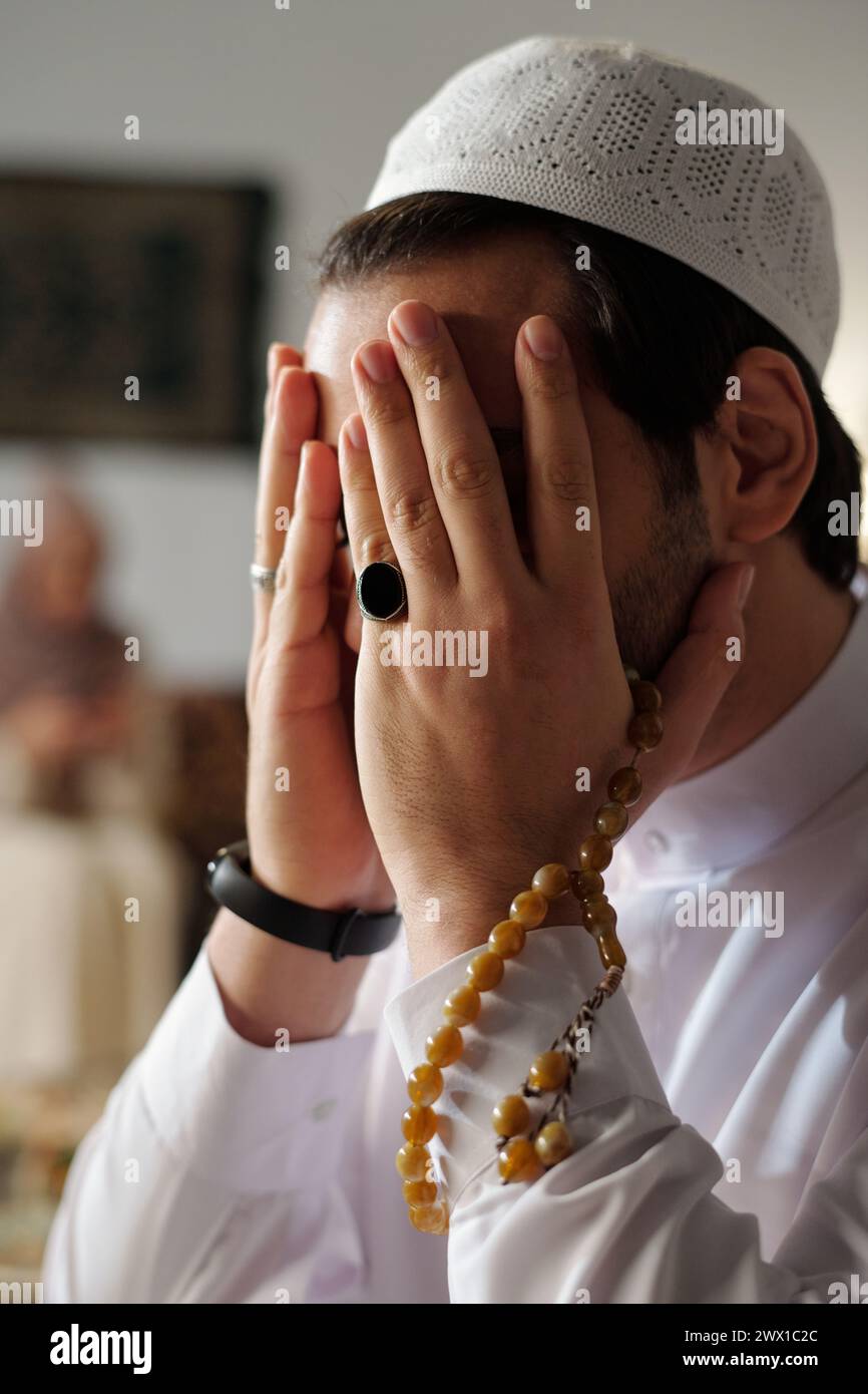 Vertical closeup of unrecognizable muslim man wearing taqiyah holding ...