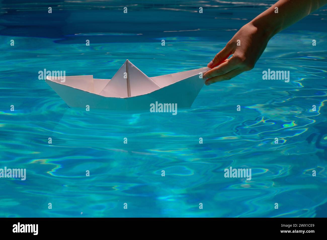 Female hand holding paper boat on the sea background. Origami paper ...