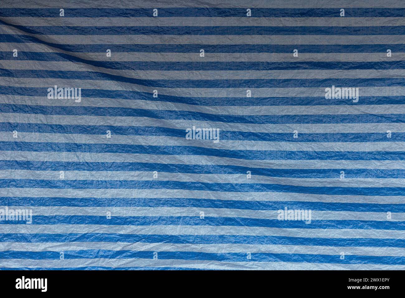Front view of wrinkled tarp with blue and white stripes. Abstract high ...