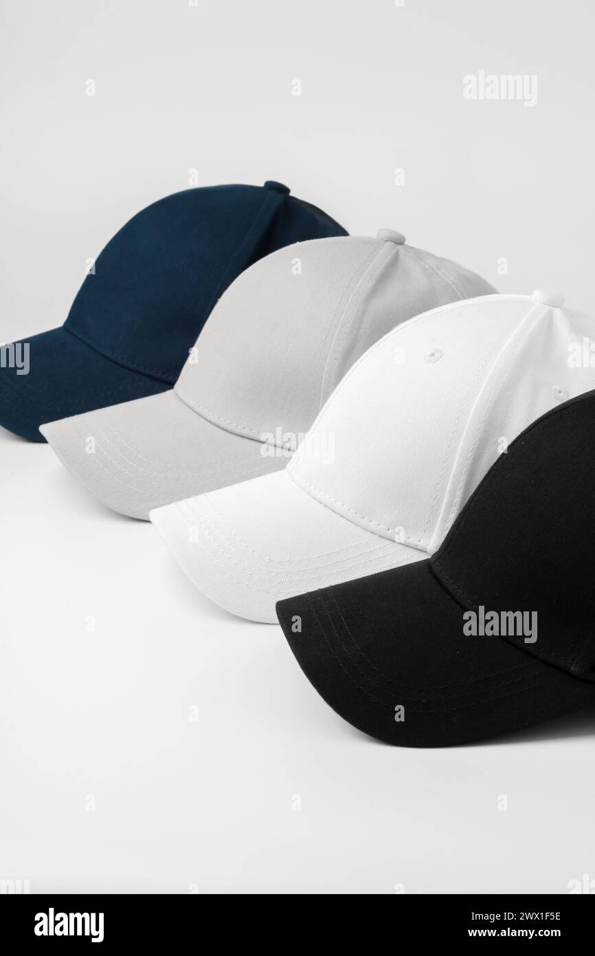 Four Baseball Caps in Black, White, Grey, and Blue Arranged on a Plain ...
