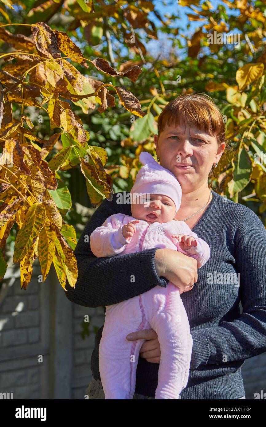 mother holds baby in her arms under a walnut tree in autumn Stock Photo ...