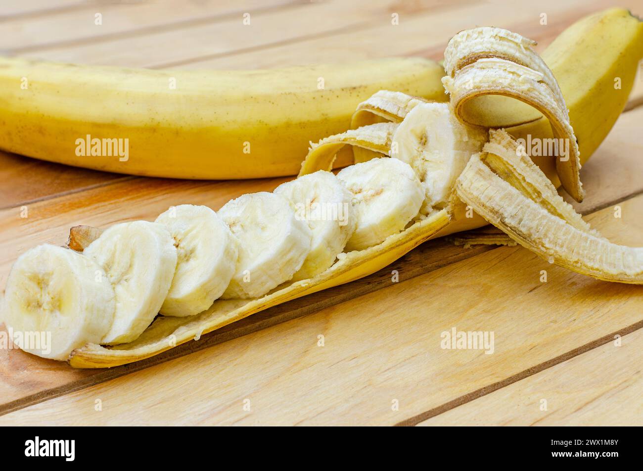 Close-up of a banana peeled to half and cut into segments, lying on a ...