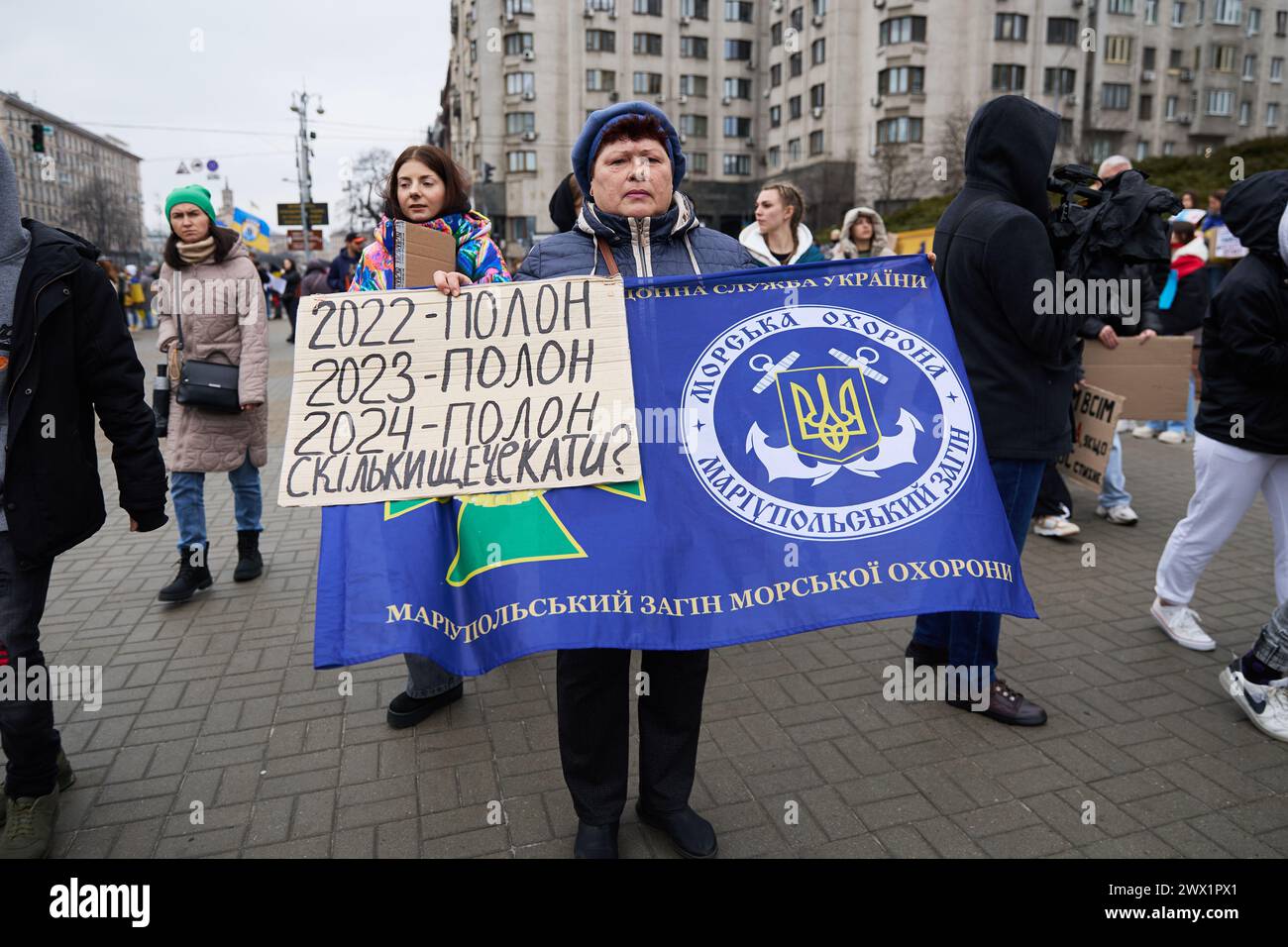 Senior woman posing with a flag of Ukrainian Coast Guard and a banner ...