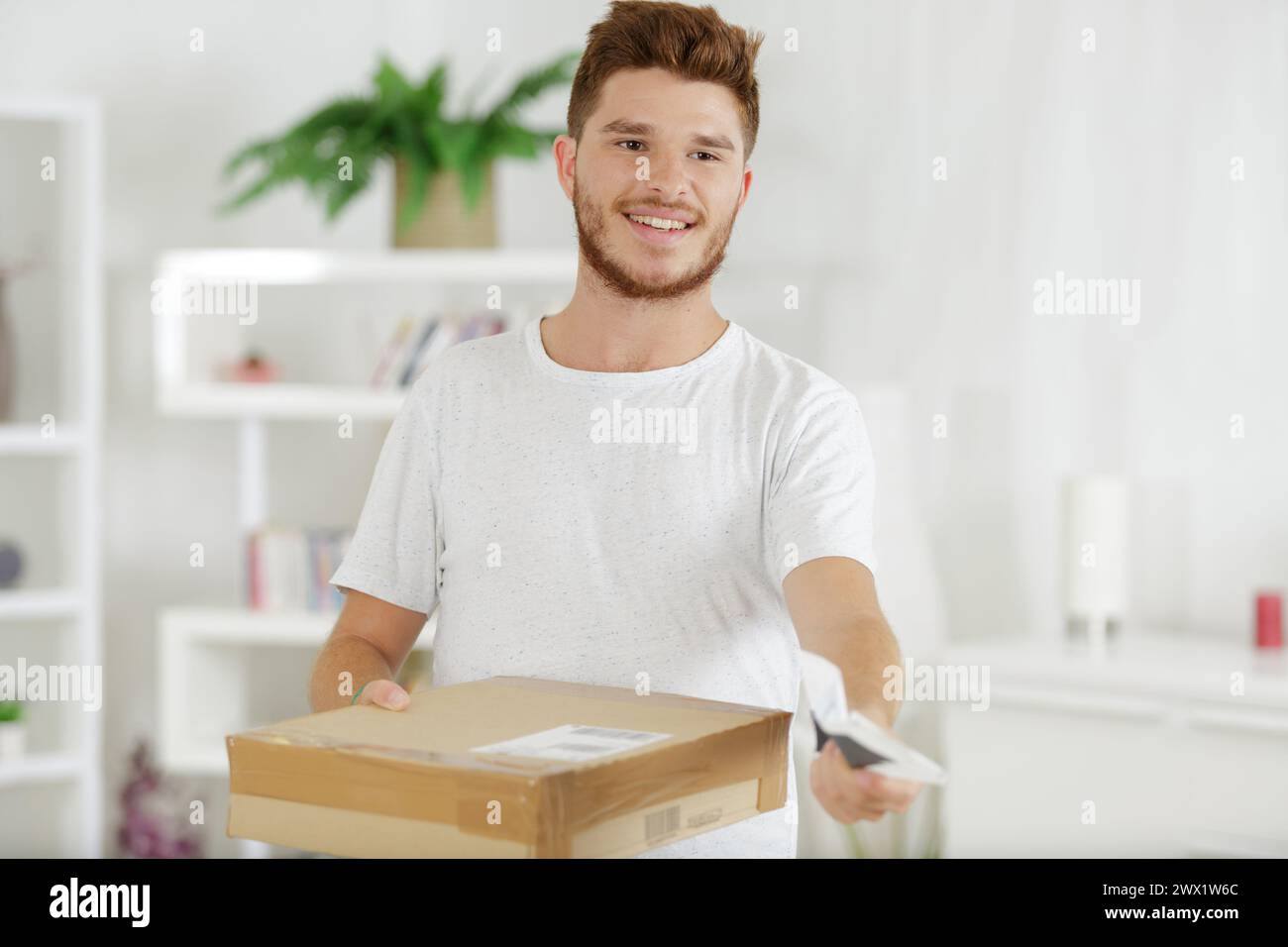 deliverer giving package box to young man Stock Photo - Alamy