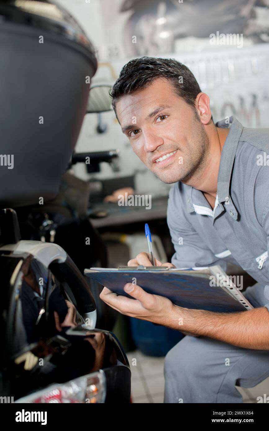 Mechanic making notes on clipboard Stock Photo - Alamy