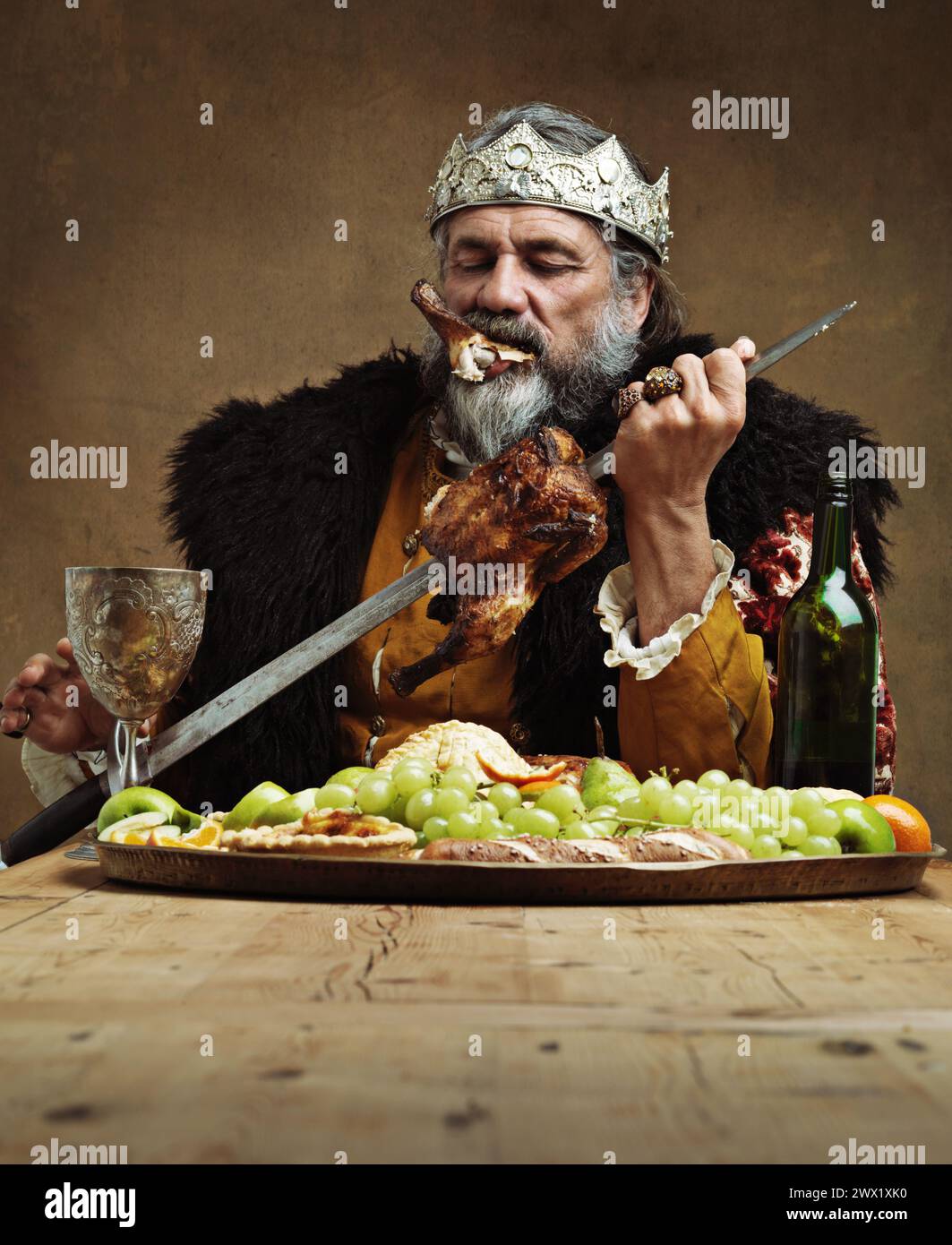 King, man and food at table with wine as royalty on dining hall for ...