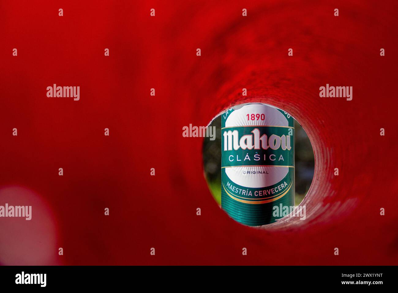 Mahou brand beer can seen through a red tube and ambient background ...