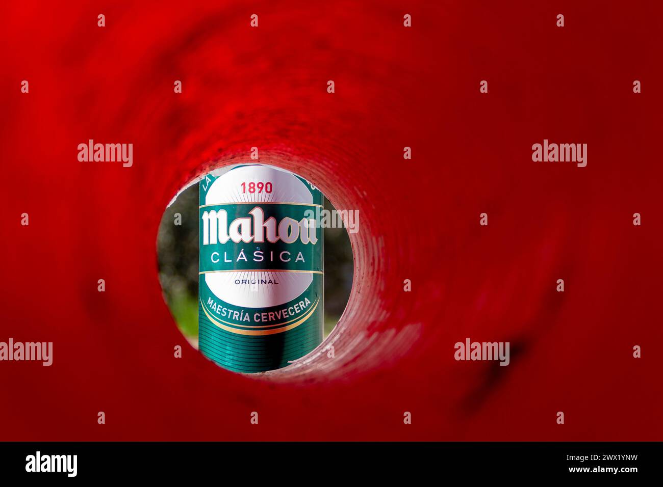 Mahou brand beer can seen through a red tube and ambient background ...