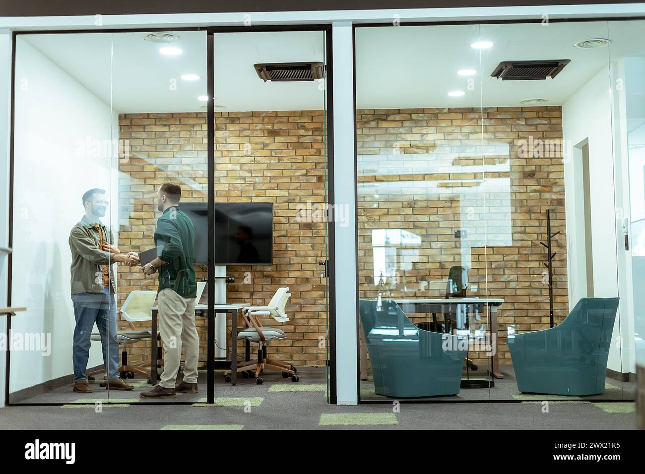 Two professionals engage in a conversation while handshaking in an ...