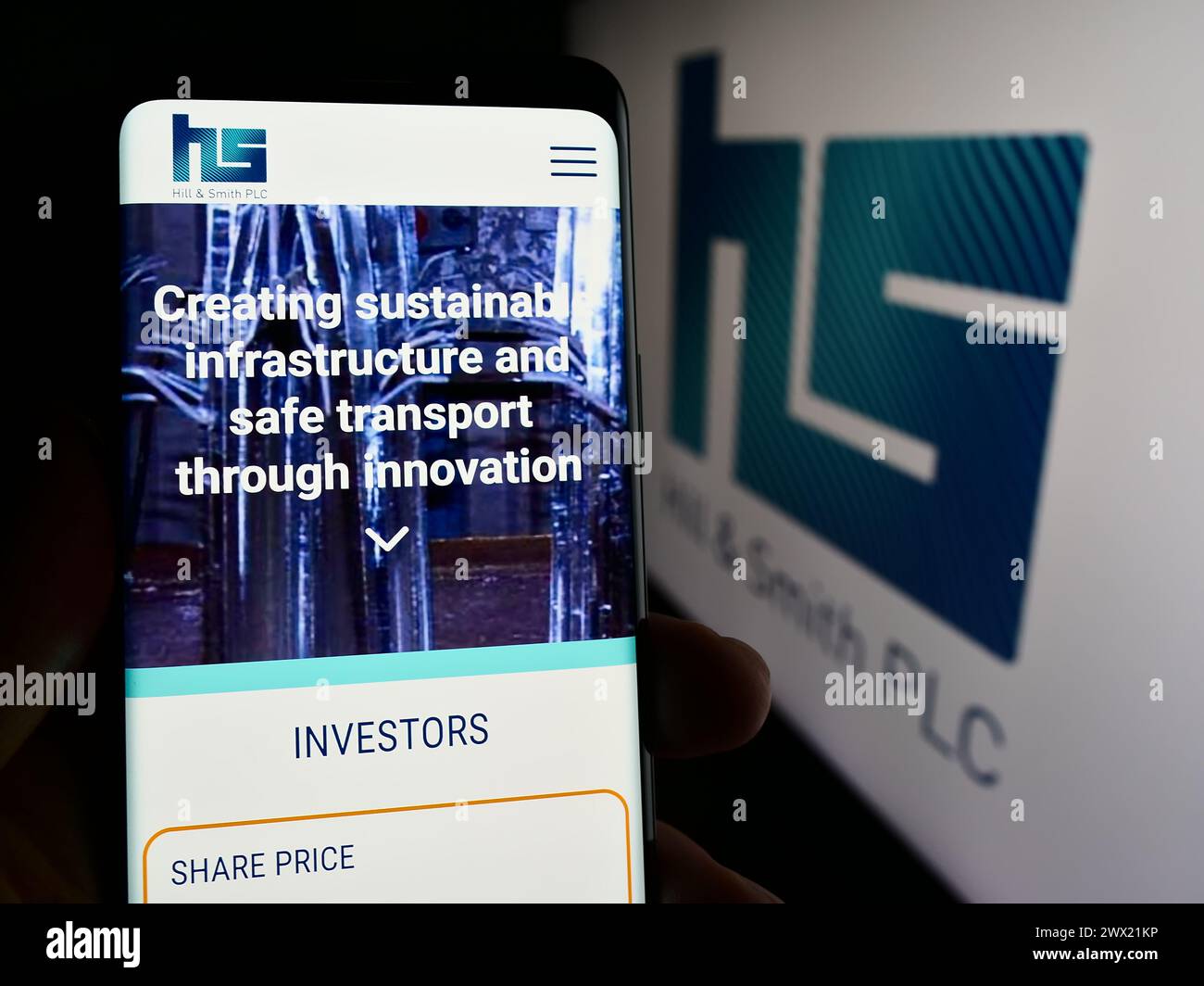 Person holding mobile phone with web page of British infrastructure ...