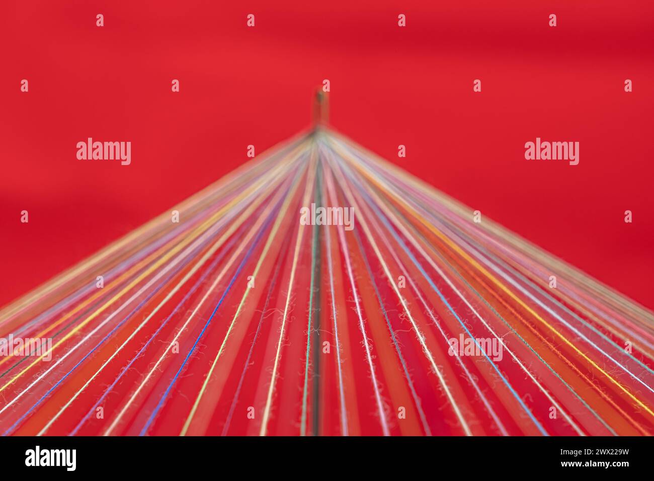 Rainbow Colored Threads Through Needle Eyelet on red background Stock ...