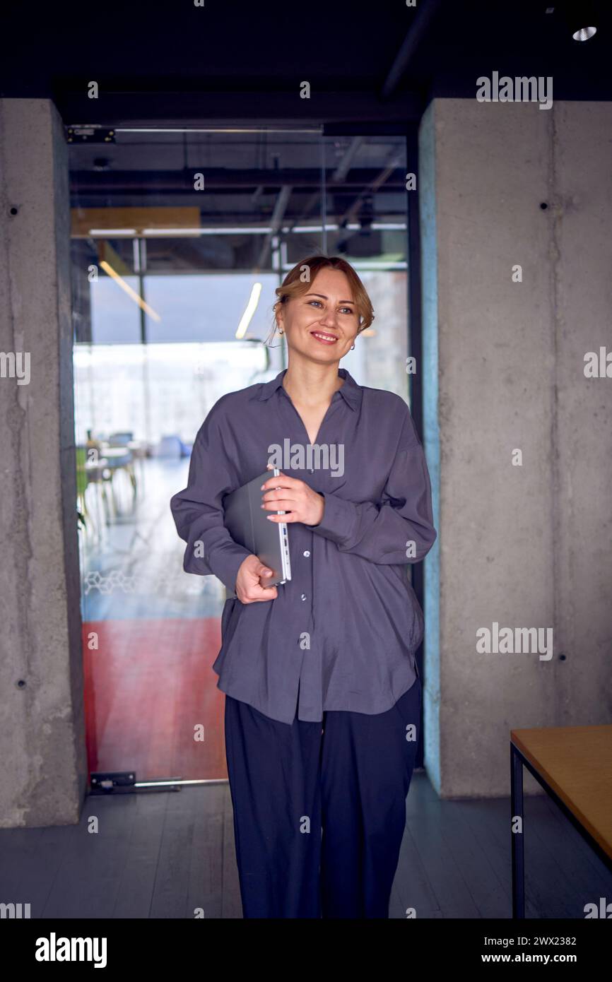 beautiful business woman enters the conference room with a laptop in ...