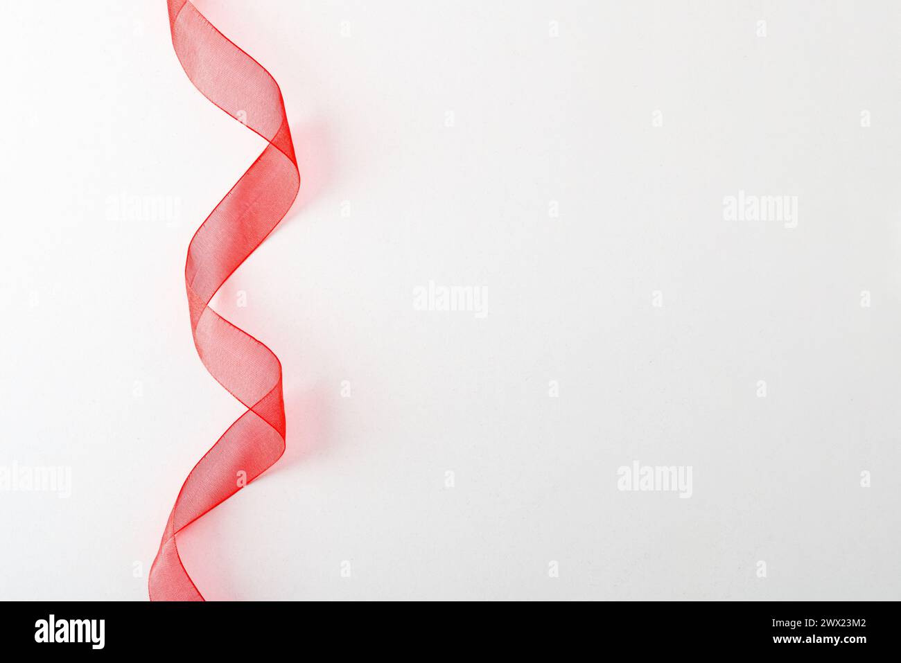 Red tulle ribbon with waves on left side on white isolated background ...
