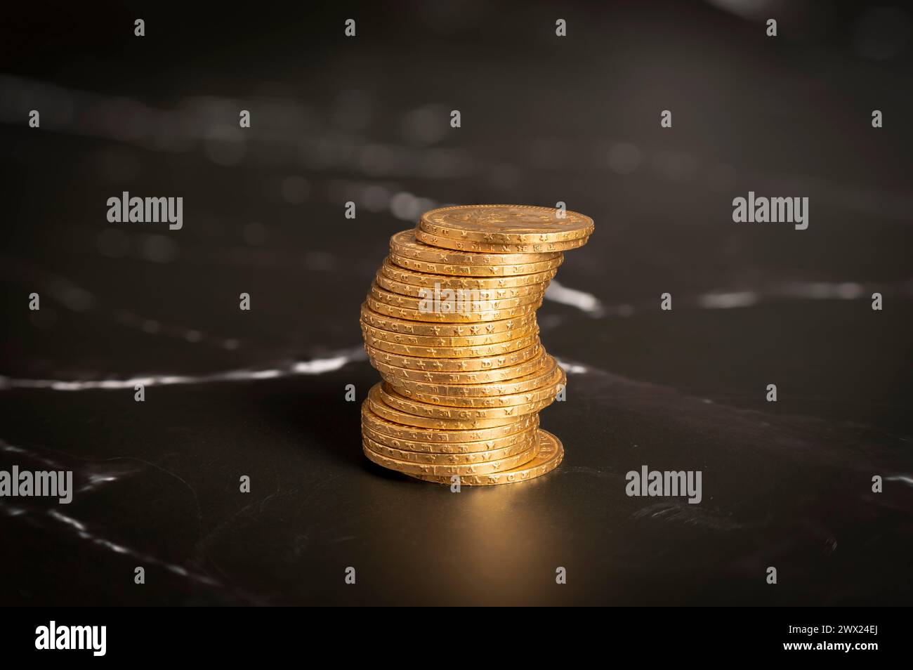 Close-up view stack of golden Louis coins on a black and white marble ...