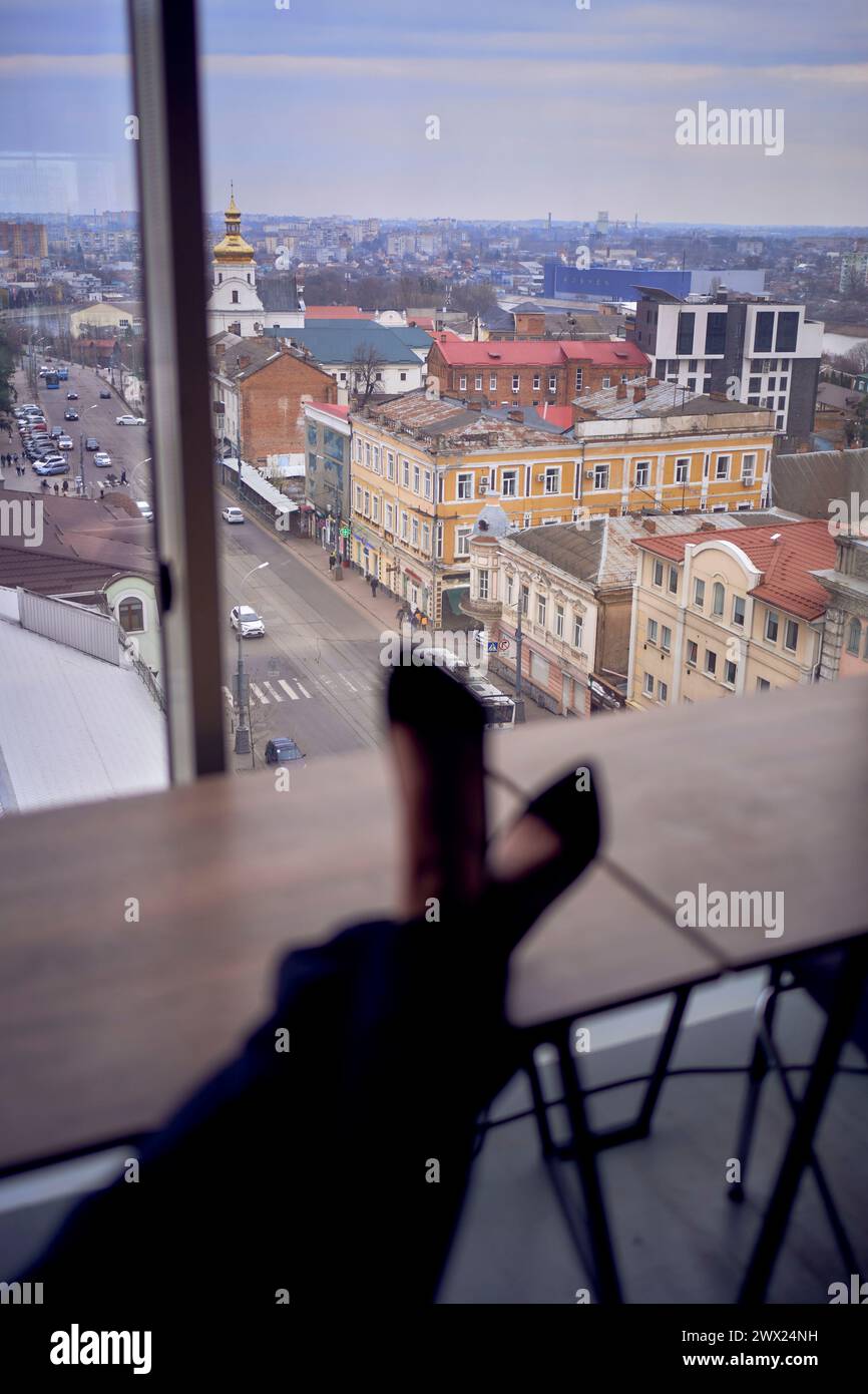 Person sitting in front of window with high heels, black pants and leg ...