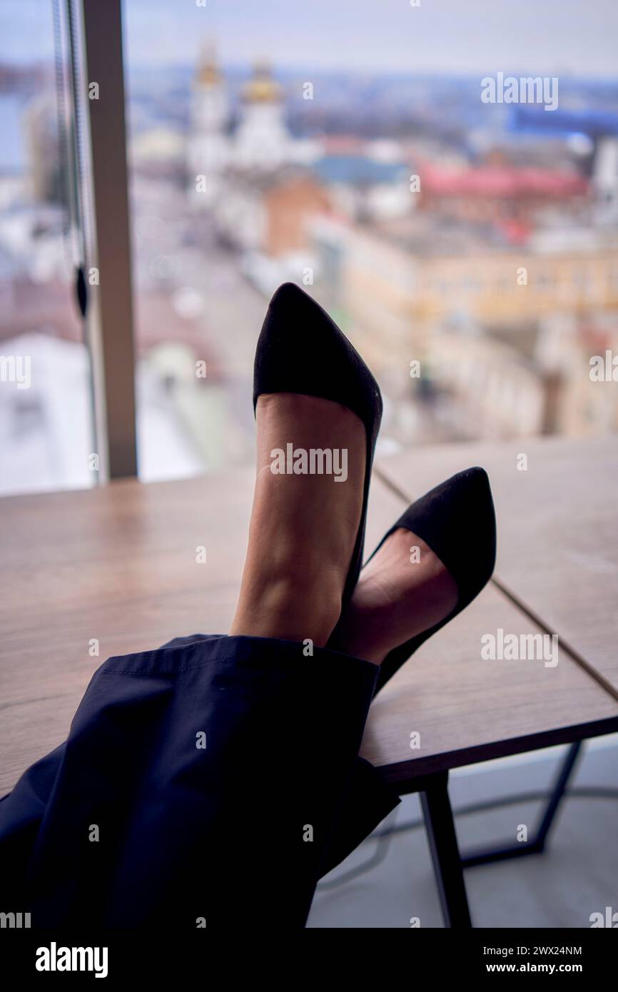 Person sitting in front of window with high heels, black pants and leg ...