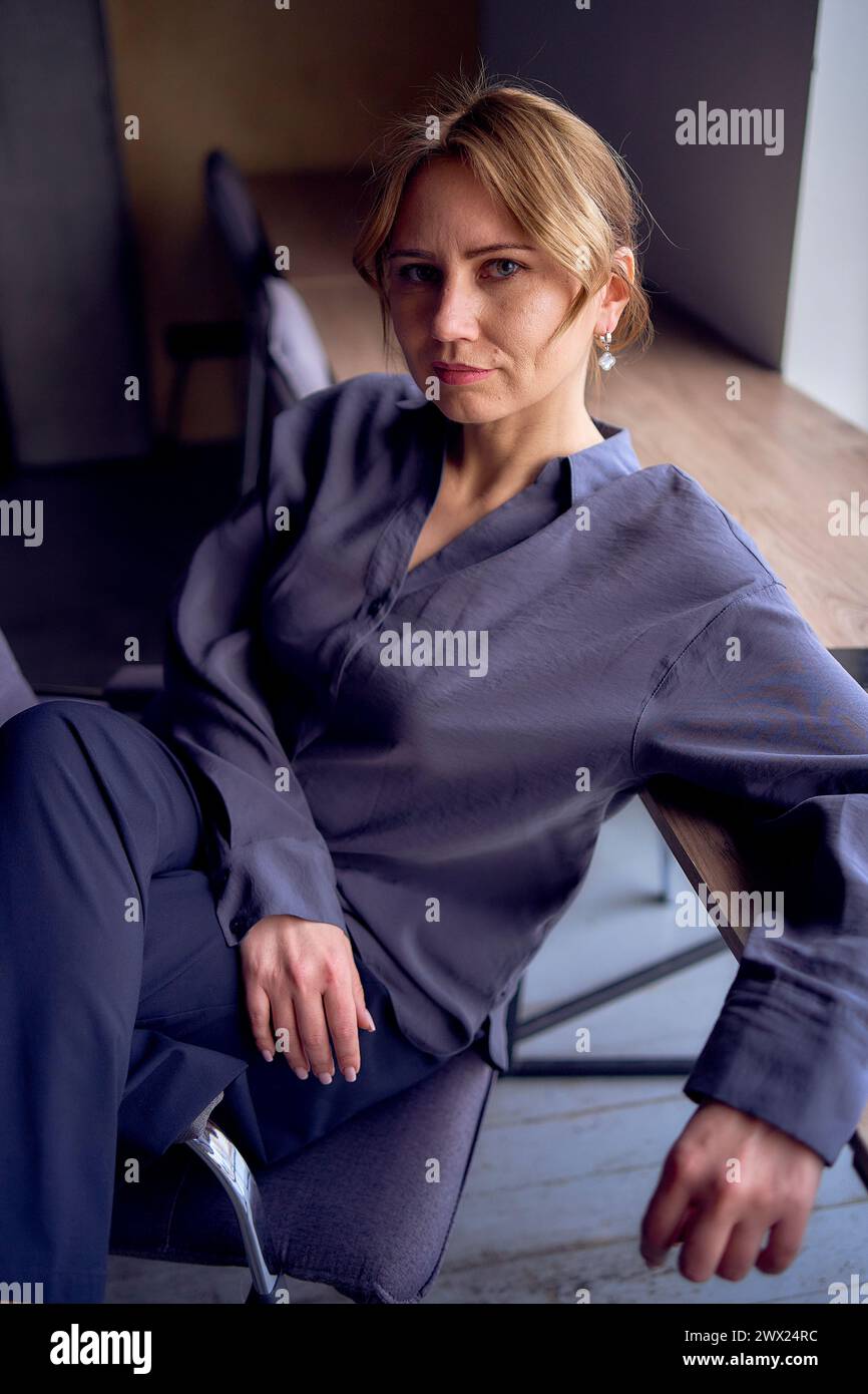 a woman sitting on chair with legs crossed over the armrest. High heels ...