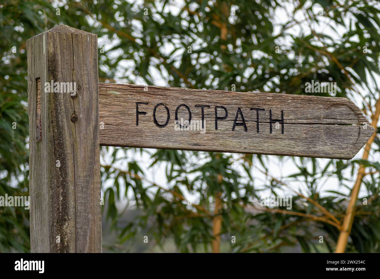 A brown wooden footpath sign shows the direction of a footpath for ...