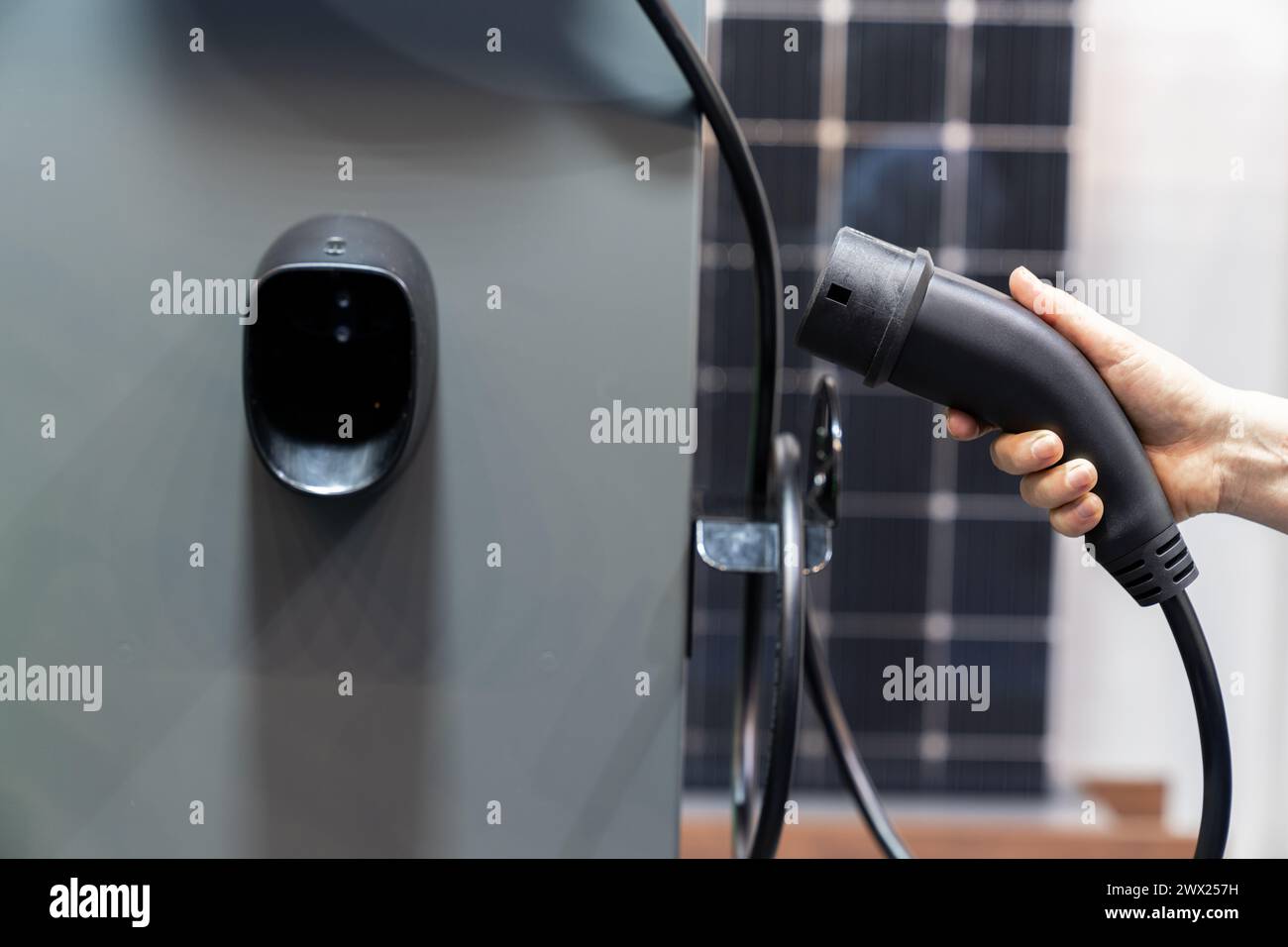 Hand with electric vehicles charging plug on a background of solar ...