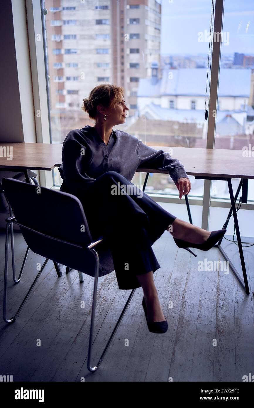 a woman sitting on chair with legs crossed over the armrest. High heels ...