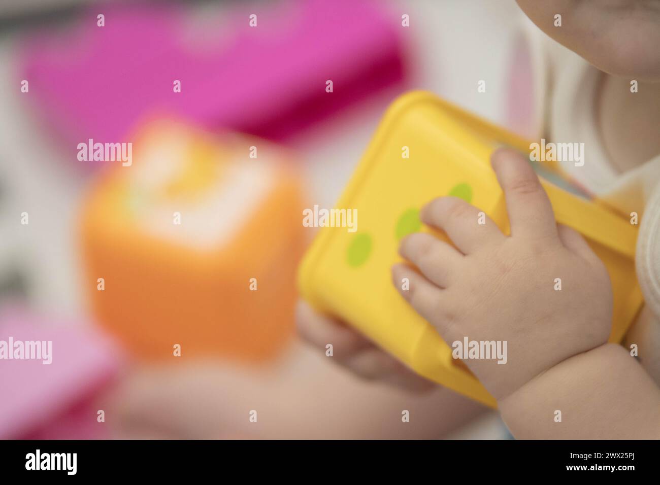 Child playfully handles blocks and other toys at childcare while ...