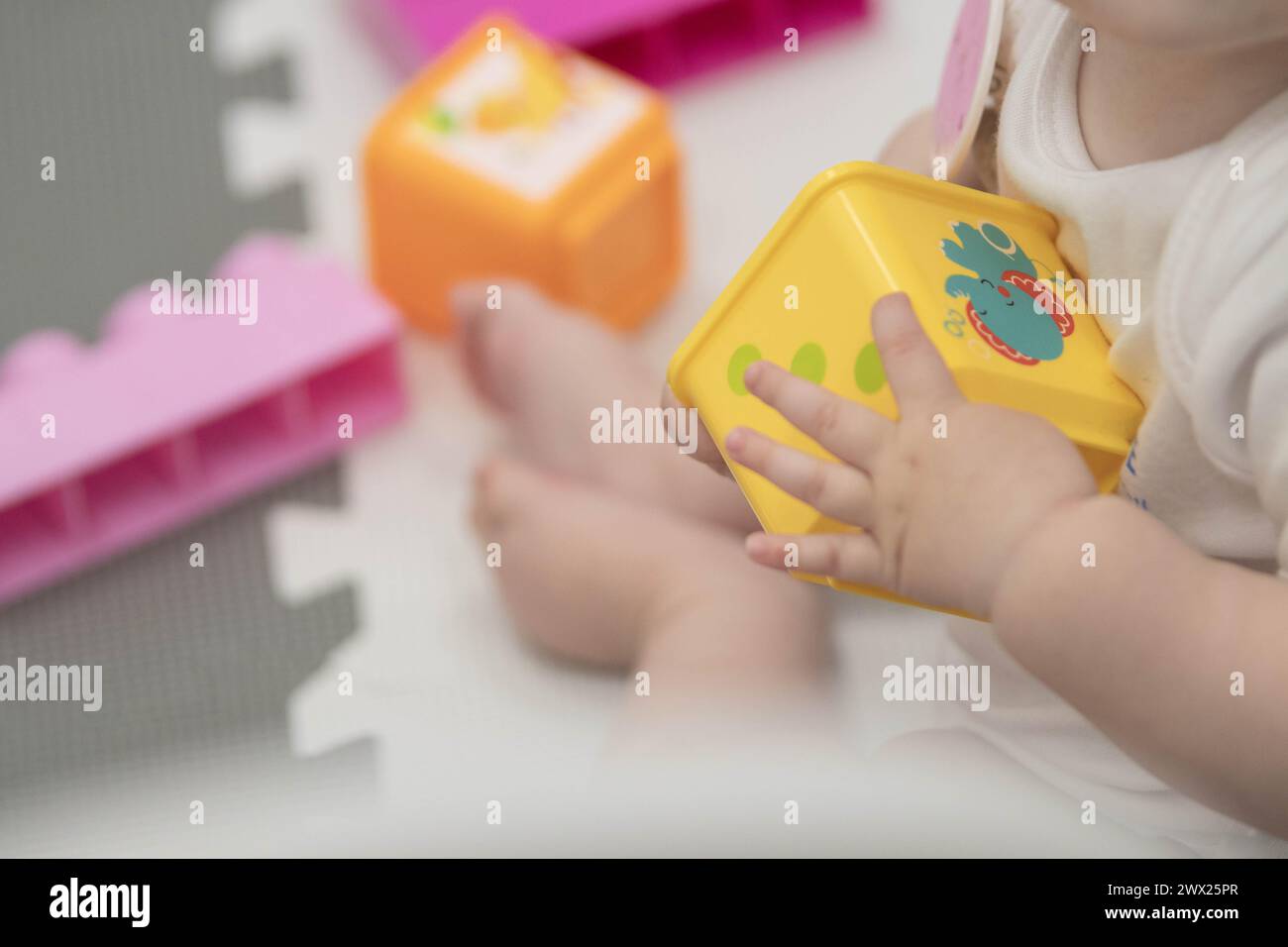 Child playfully handles blocks and other toys at childcare while ...