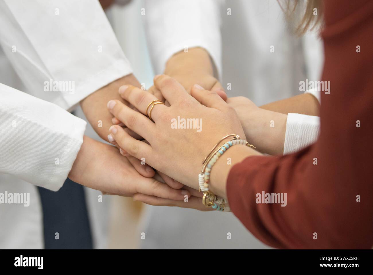 Teacher holds students hands in pile while gently talking to them in a ...