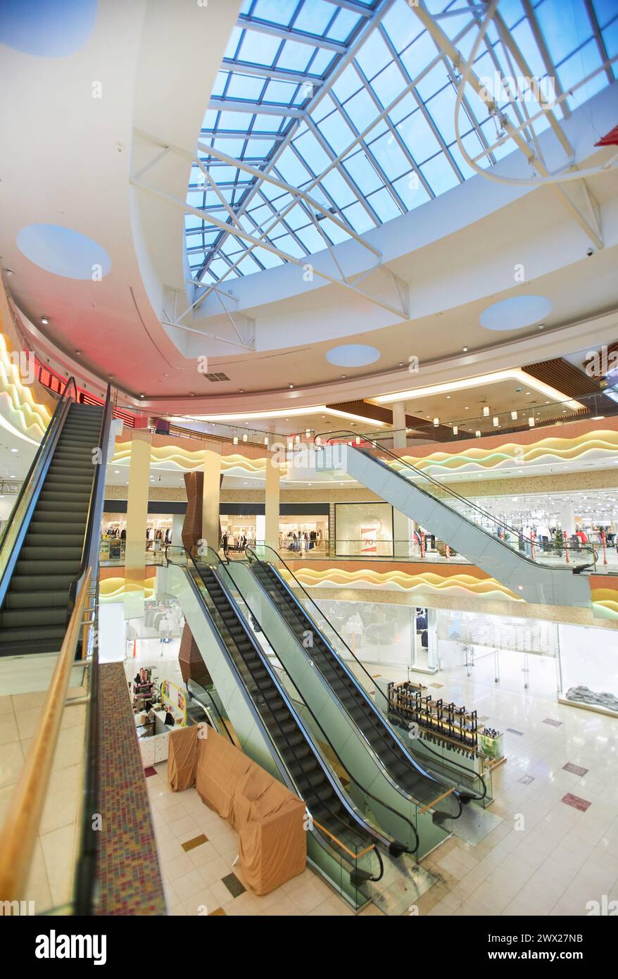 Vertical wide angle view at shopping mall interior with escalator and ...