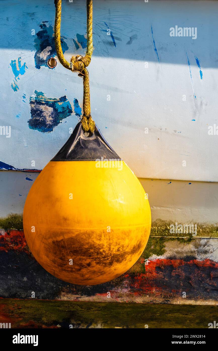 A polyform yellow net buoy hanging over the hull of a boat In Newquay ...