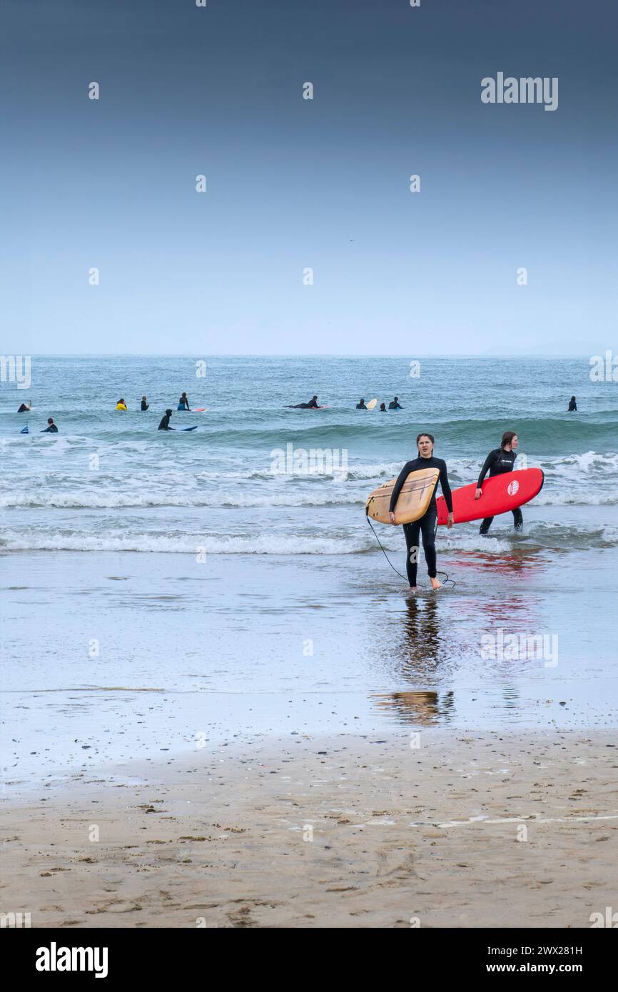Female surfers carrying their surfboards and walking out of the sea at ...