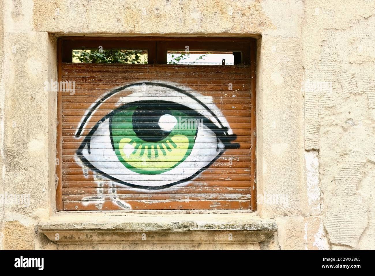 Painted large green eye graffiti on the shutter of an abandoned ...