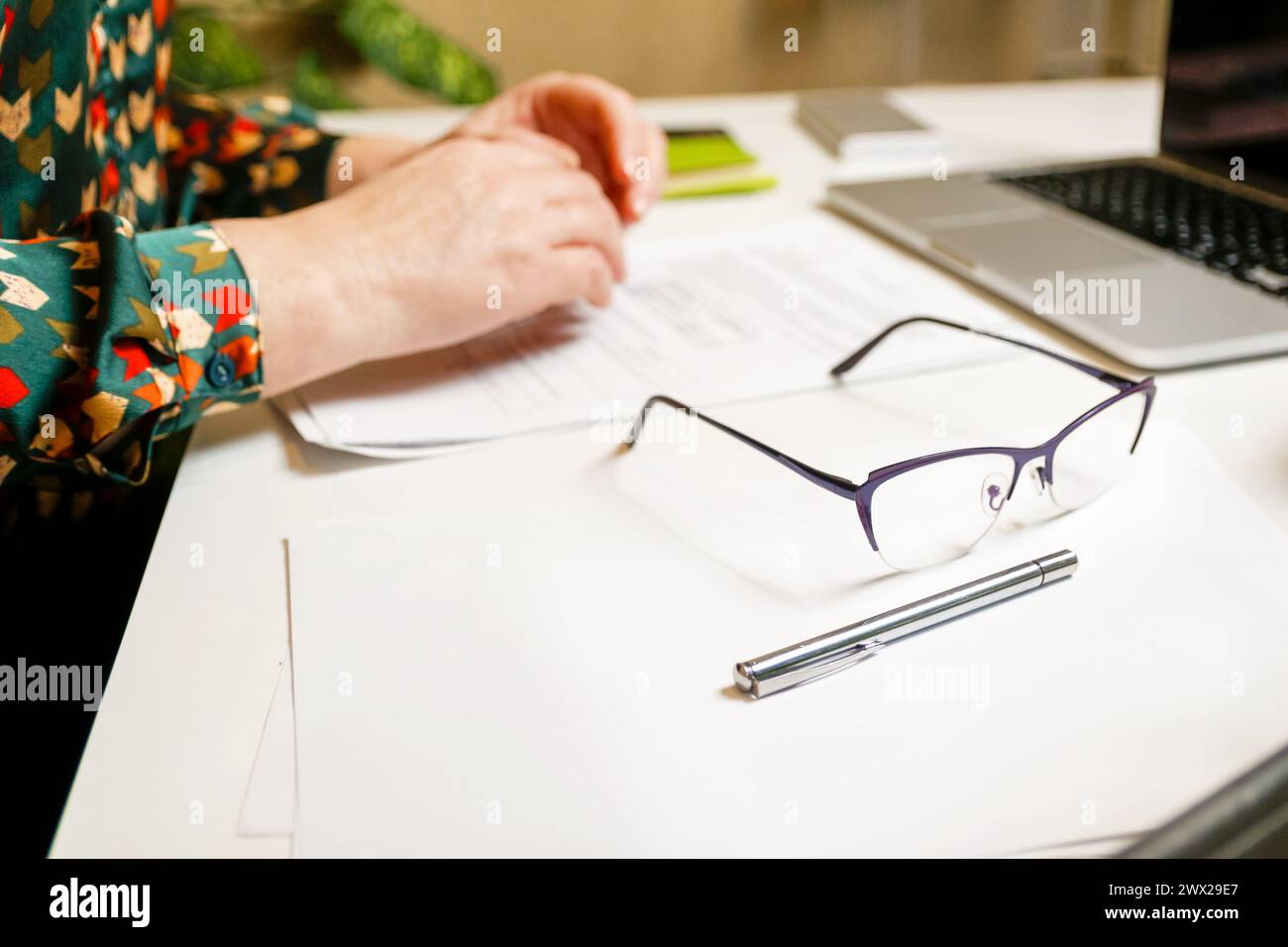 A professional woman's workspace featuring stylish eyeglasses placed on ...