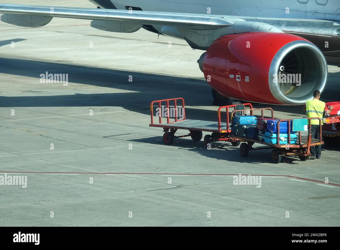 Airport baggage handler with trailer transporting suitcases between the ...