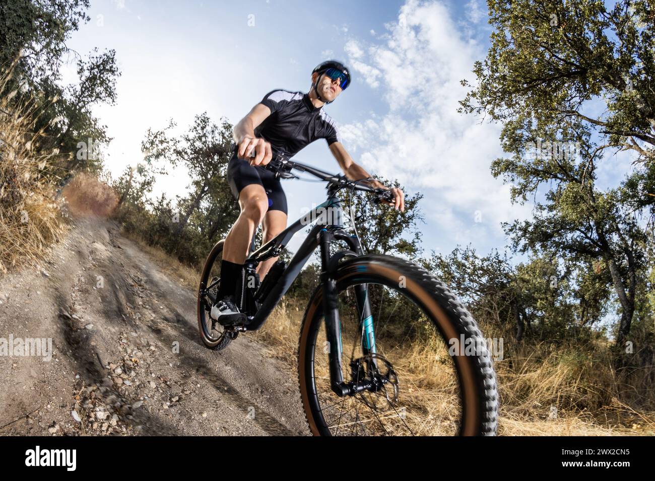 front view of a young adult mountain biker riding up a trail in a ...
