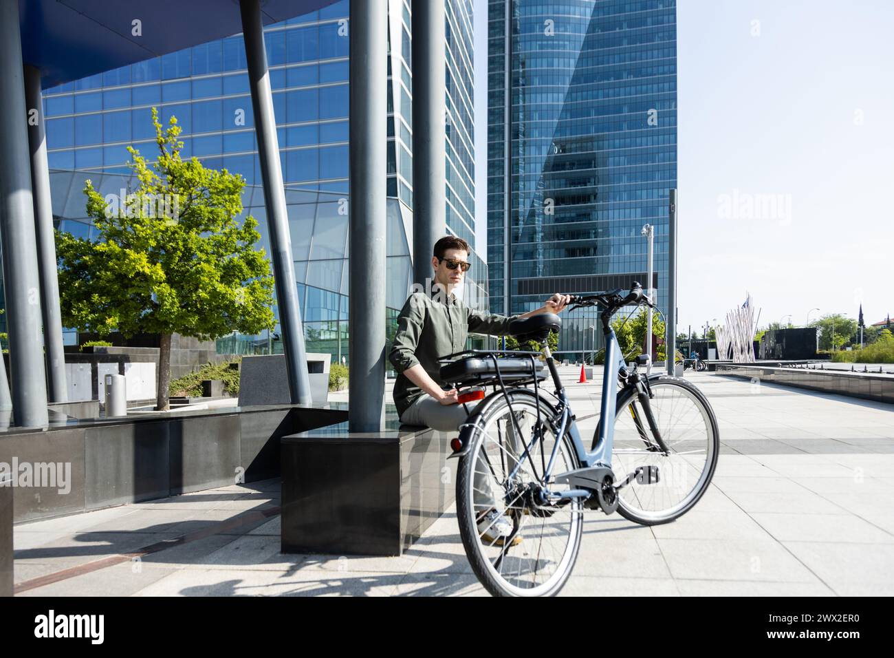 young businessman rides e-bike on his way to the tower where his office ...