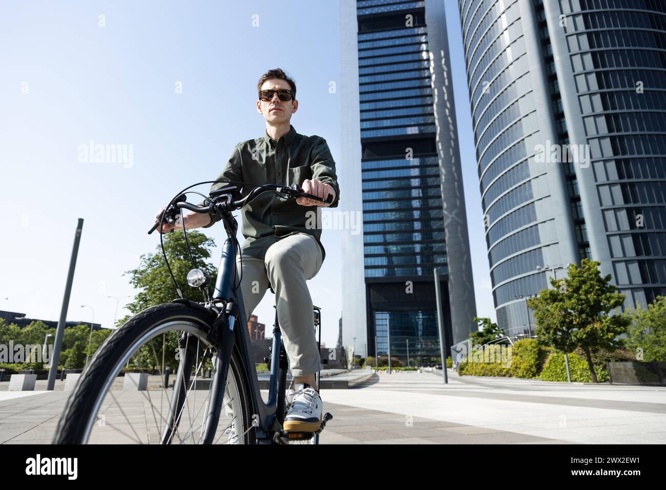 young businessman rides e-bike on his way to the tower where his office ...